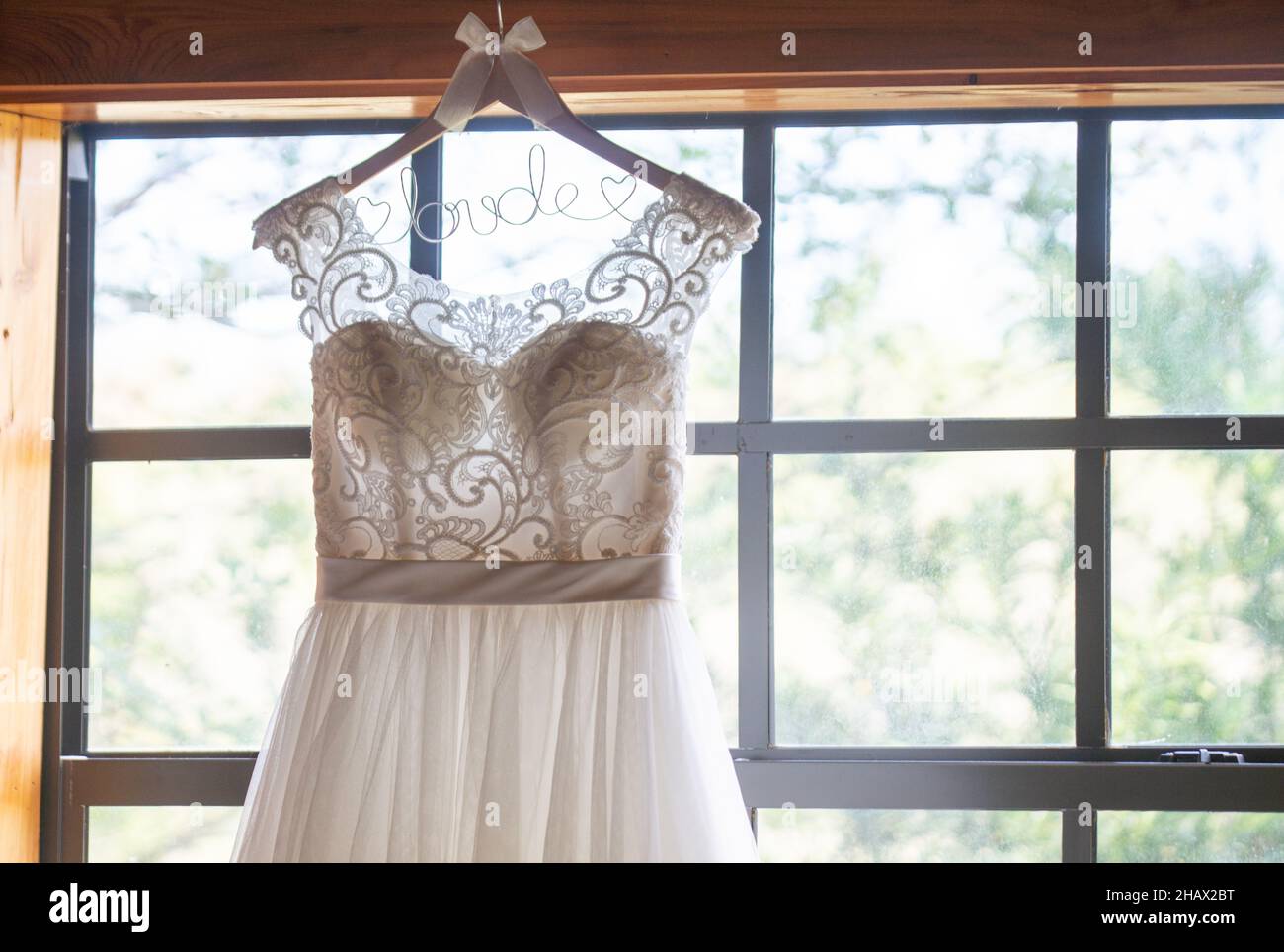 white lace wedding dress hanging from window Stock Photo - Alamy