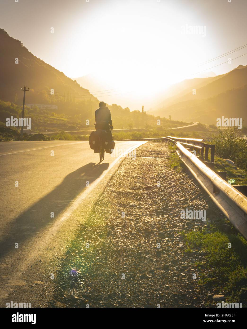 Person on loaded bicycle is passing georgian road sign with mountains ...