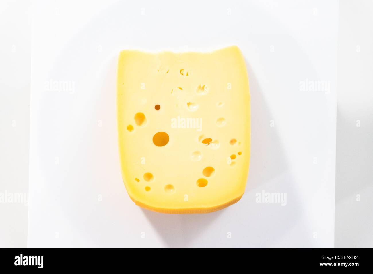 Large slice of semi soft part skim cheese on a white cutting board ...