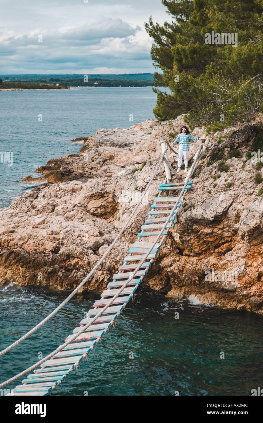 woman crossing suspension bridge sea on background summer time Stock ...