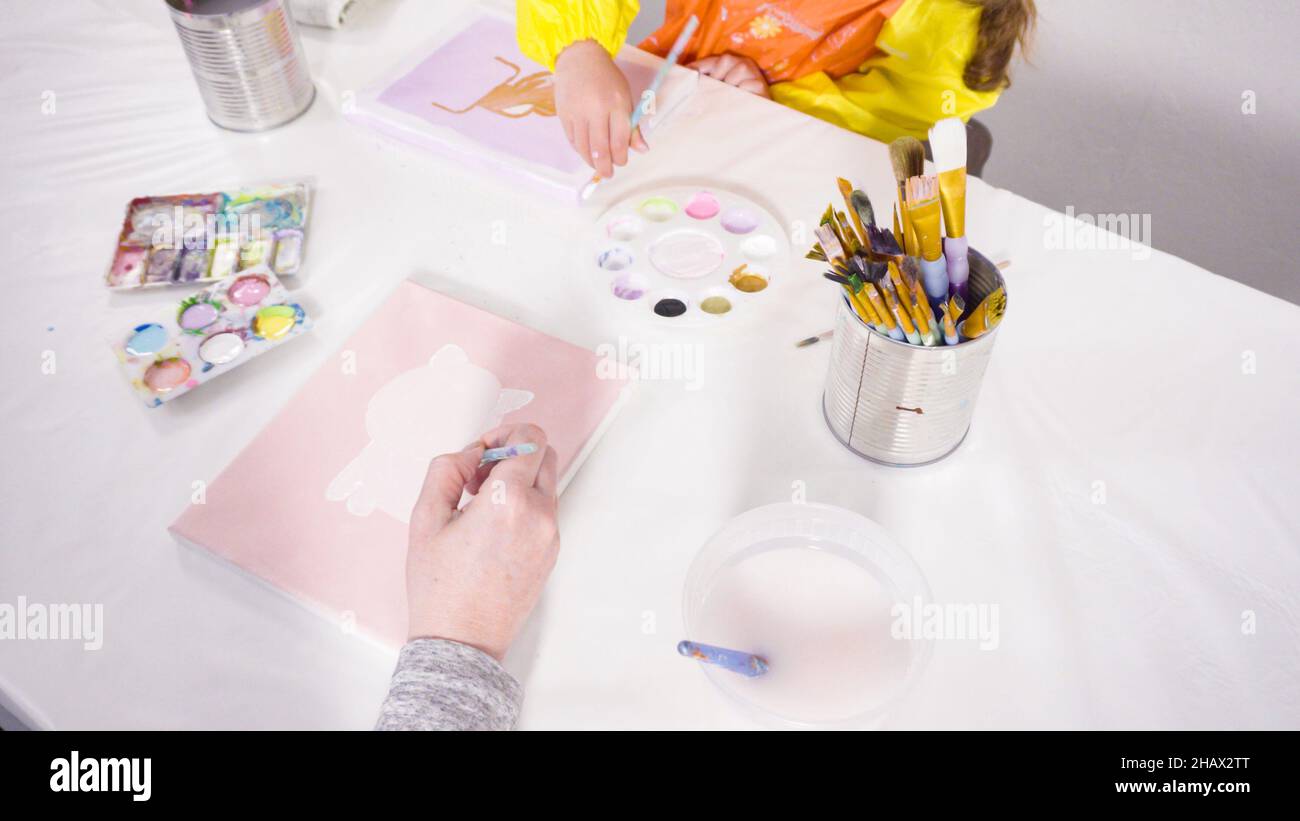 Little girl painting with acrylic paint on canvas with her mother for a ...