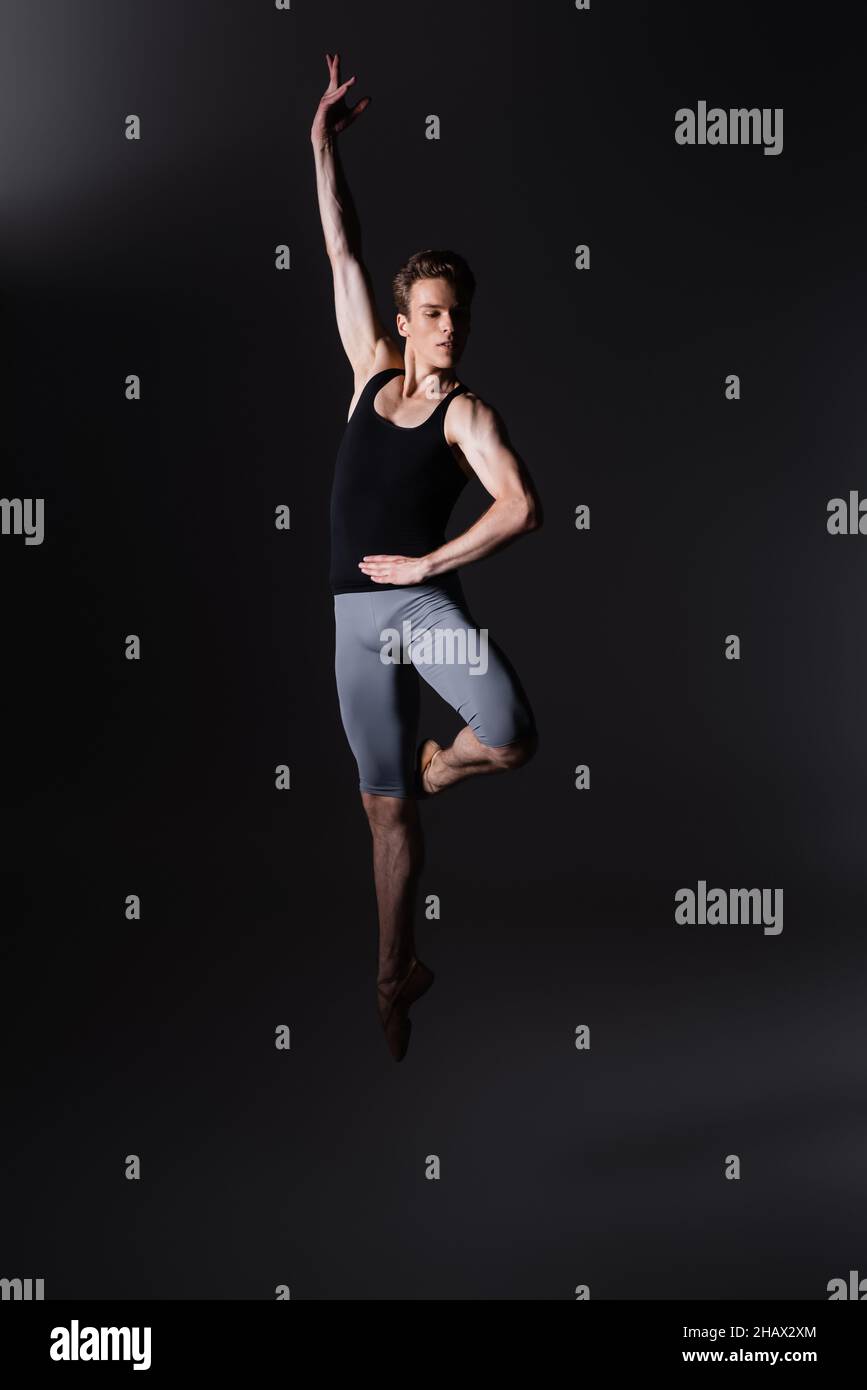 young and graceful dancer gesturing while performing ballet dance while ...