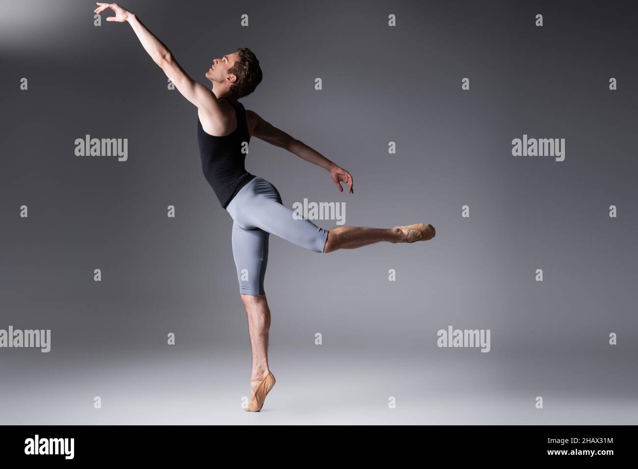full length of graceful ballet dancer performing ballet dance on dark ...