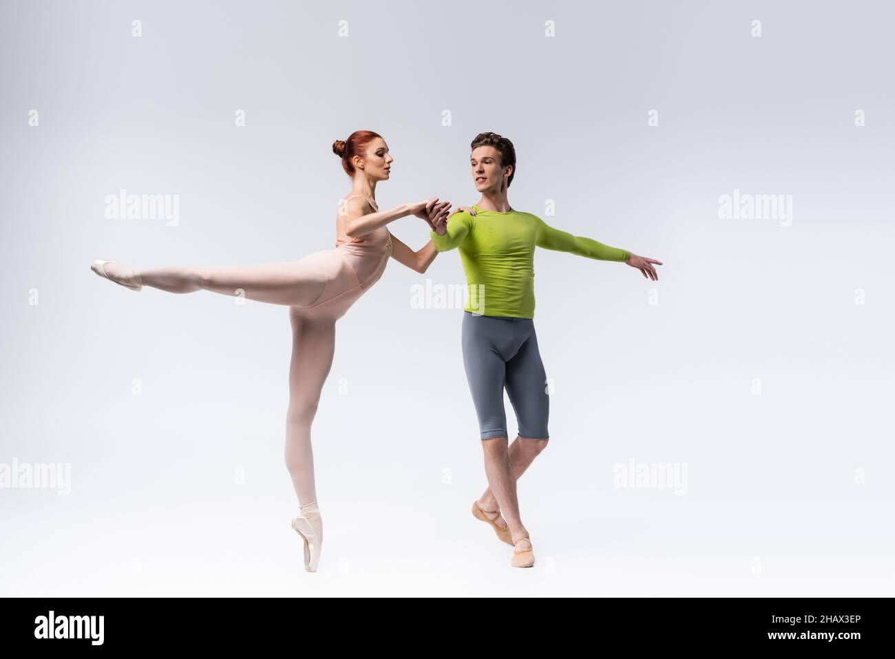full length of elegant dancers performing ballet dance on grey Stock ...