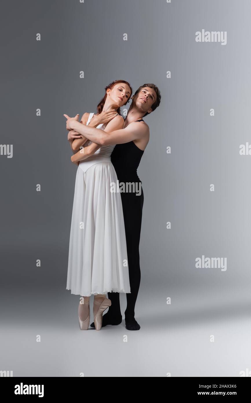 full length of ballet dancer hugging graceful ballerina in white dress ...