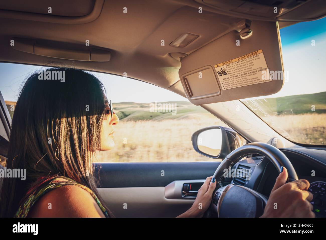 Young attractive girl in drivers seat looks straight and holds hands on ...