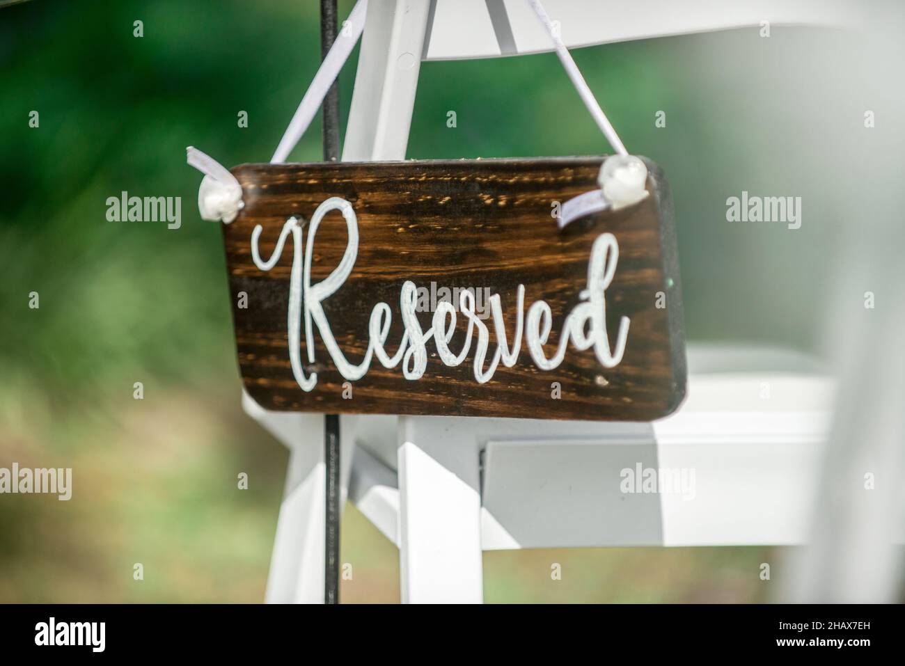 "reserved" seating sign on wood board hanging from white chair at ...