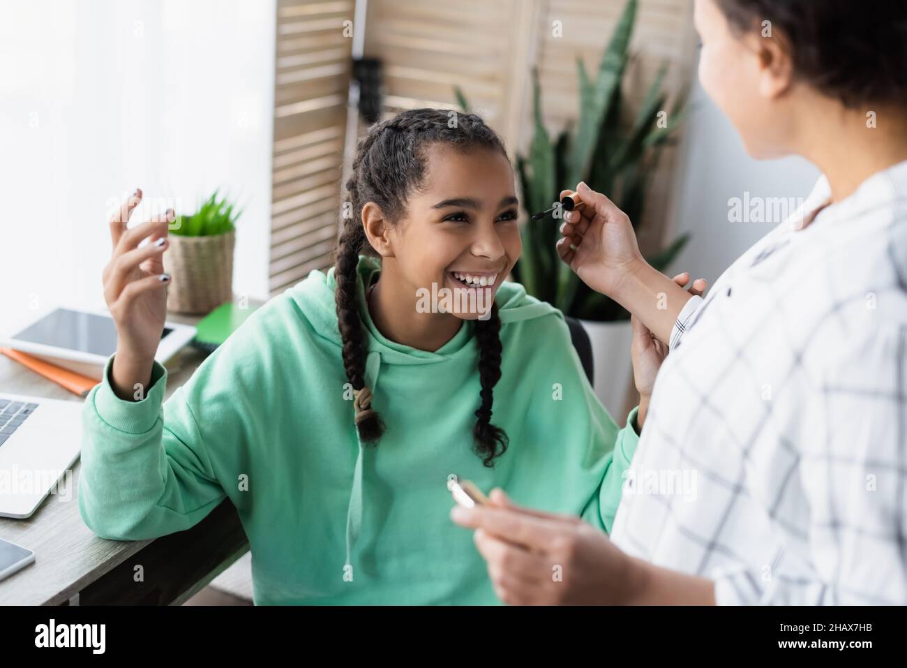 blurred african american woman holding mascara while doing mascara to ...