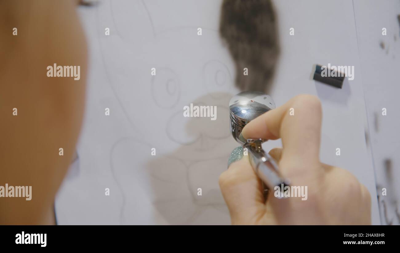 Woman artist learns to paint with airbrush with acrylic dye, paper and ...