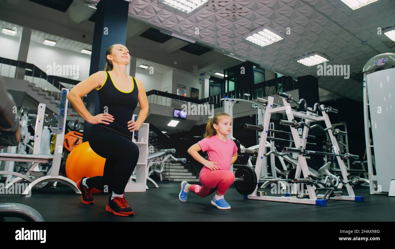 Mother and daughter in the gym, family performs physical doing e Stock ...