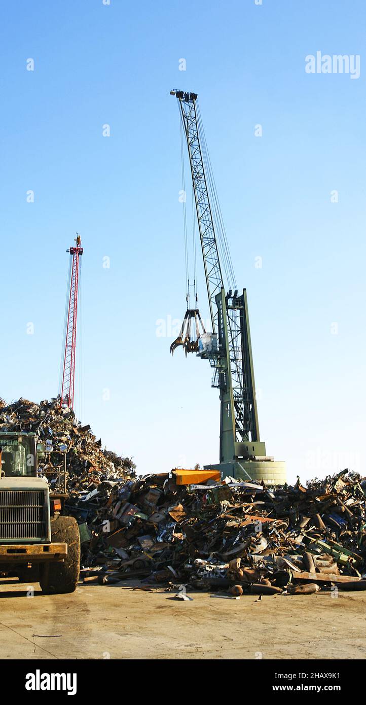 Crane with mountain of scrap metal in the industrial area of the port ...