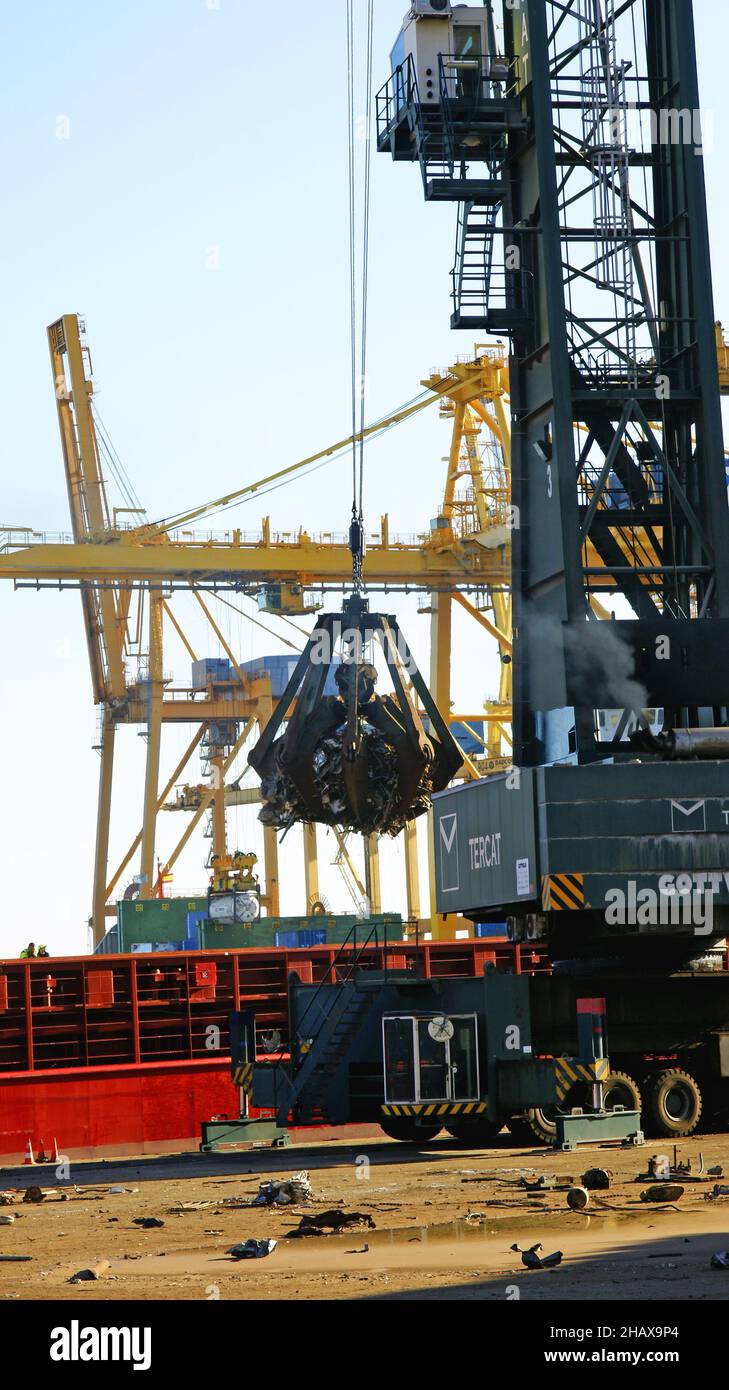 Crane with mountain of scrap metal loading a ship in the industrial ...