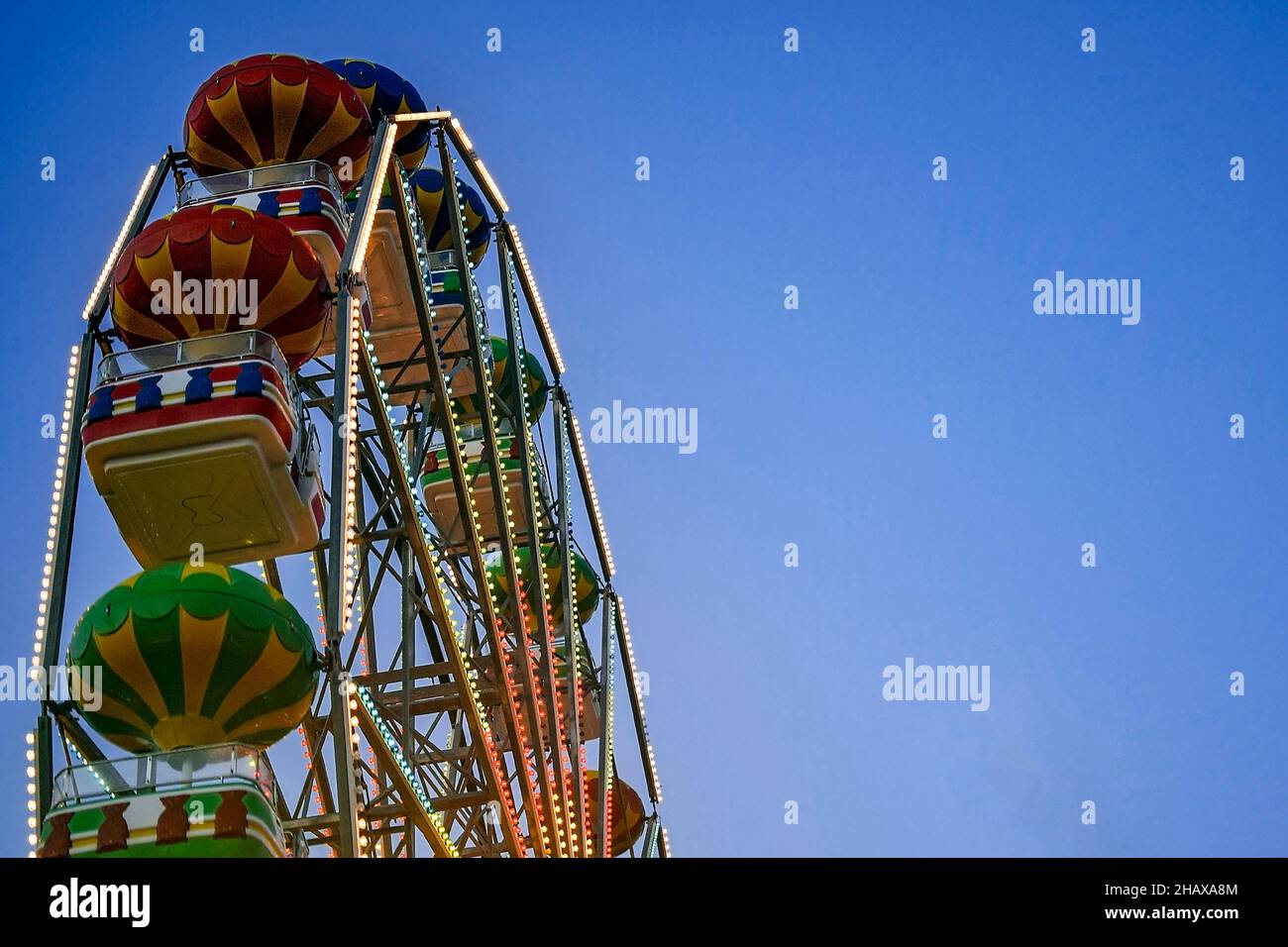 Large multi-colored ferris wheel against blue sky. Bright illumination ...