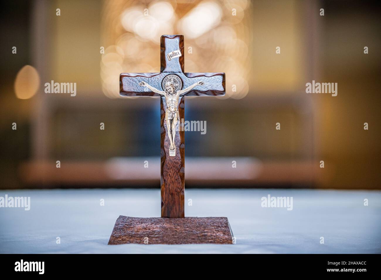 Gold Jesus on wood cross and stand sculpture on white table with warm ...