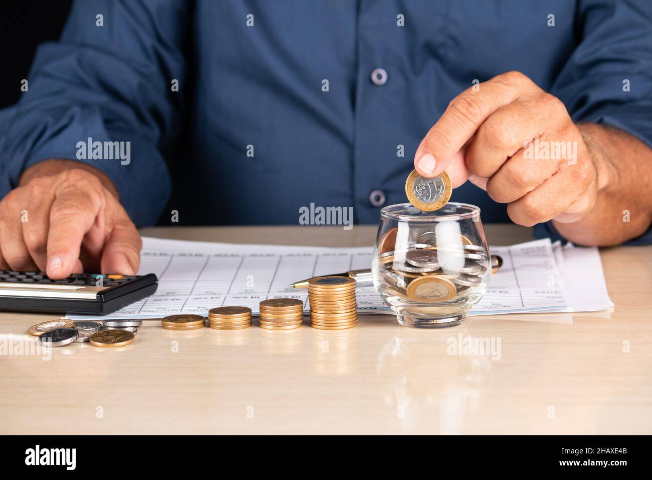Businessman holding coins and putting into glass pot. Saving concept ...