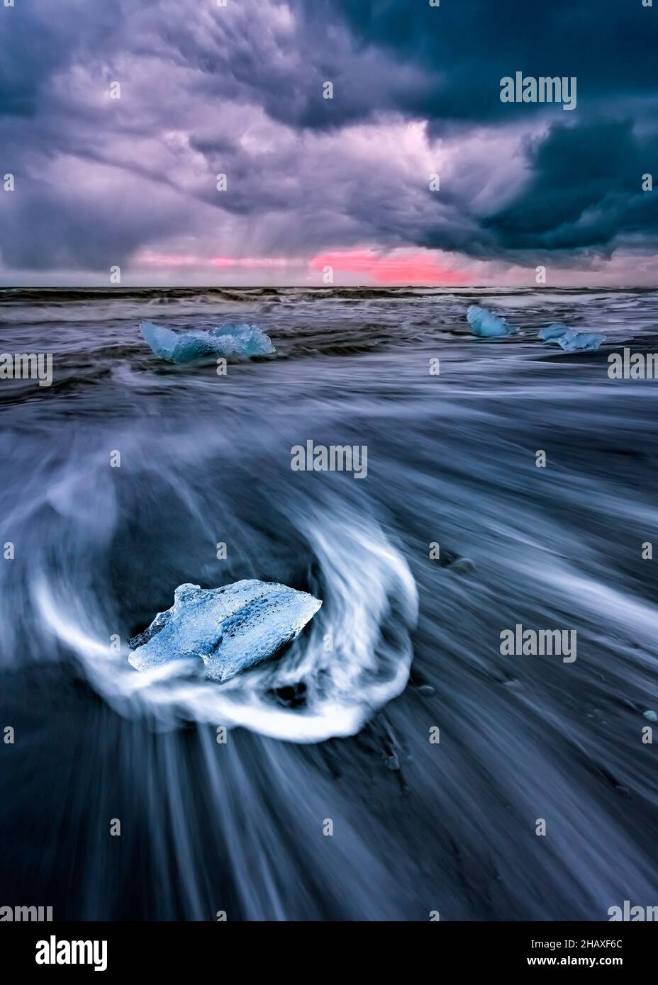 Long exposure shot of water at shore flowing back to the ocean at dusk ...