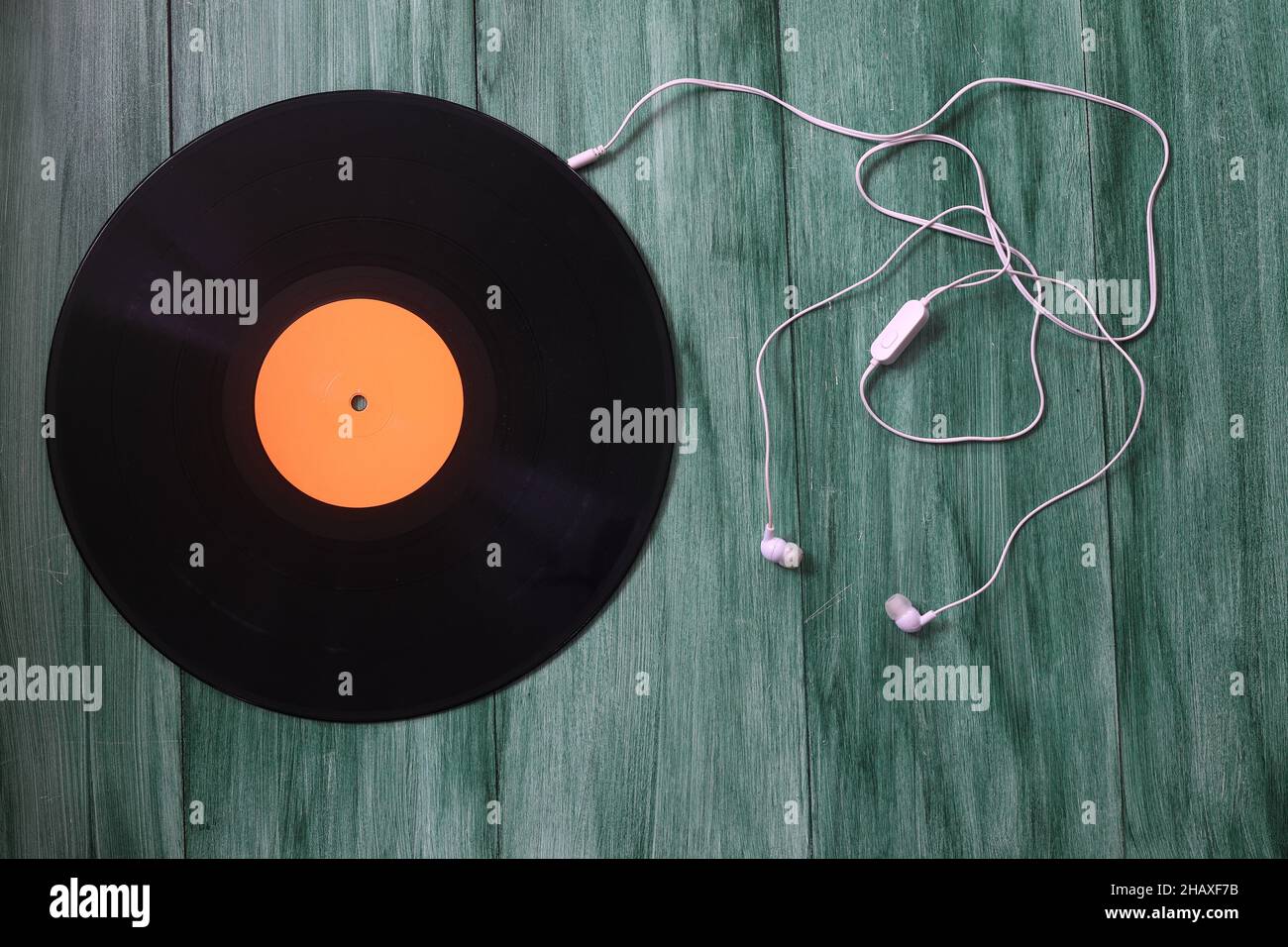 White headphones with wire and vinyl discs on an green background ...