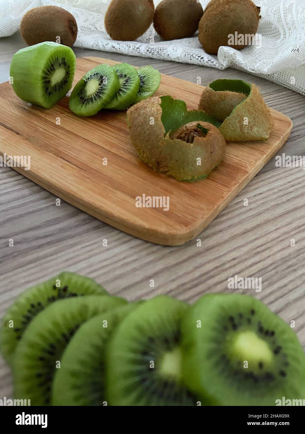 Kiwi, slices and peels of kiwis on the cutting plate and on the table ...