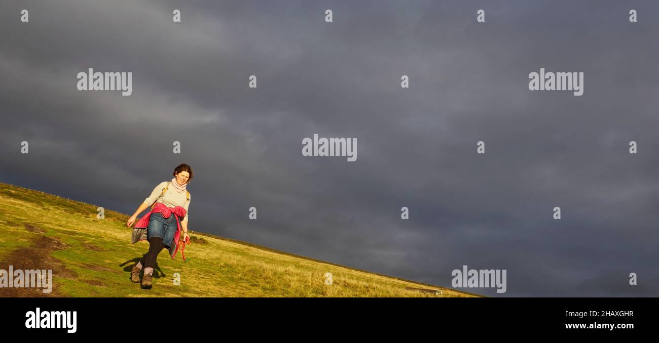 A woman walks down the snake path in the hills in the Peak District ...