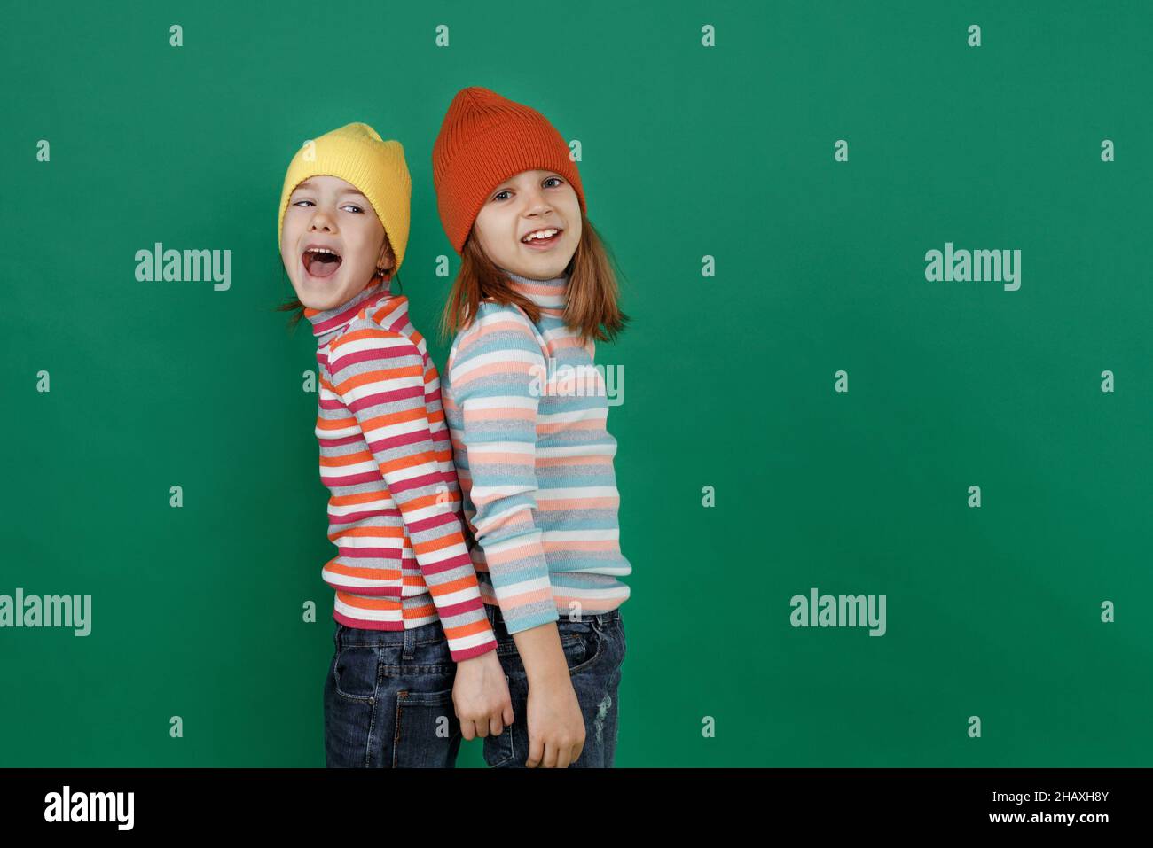 two children are standing on a green isolated background pressed back ...