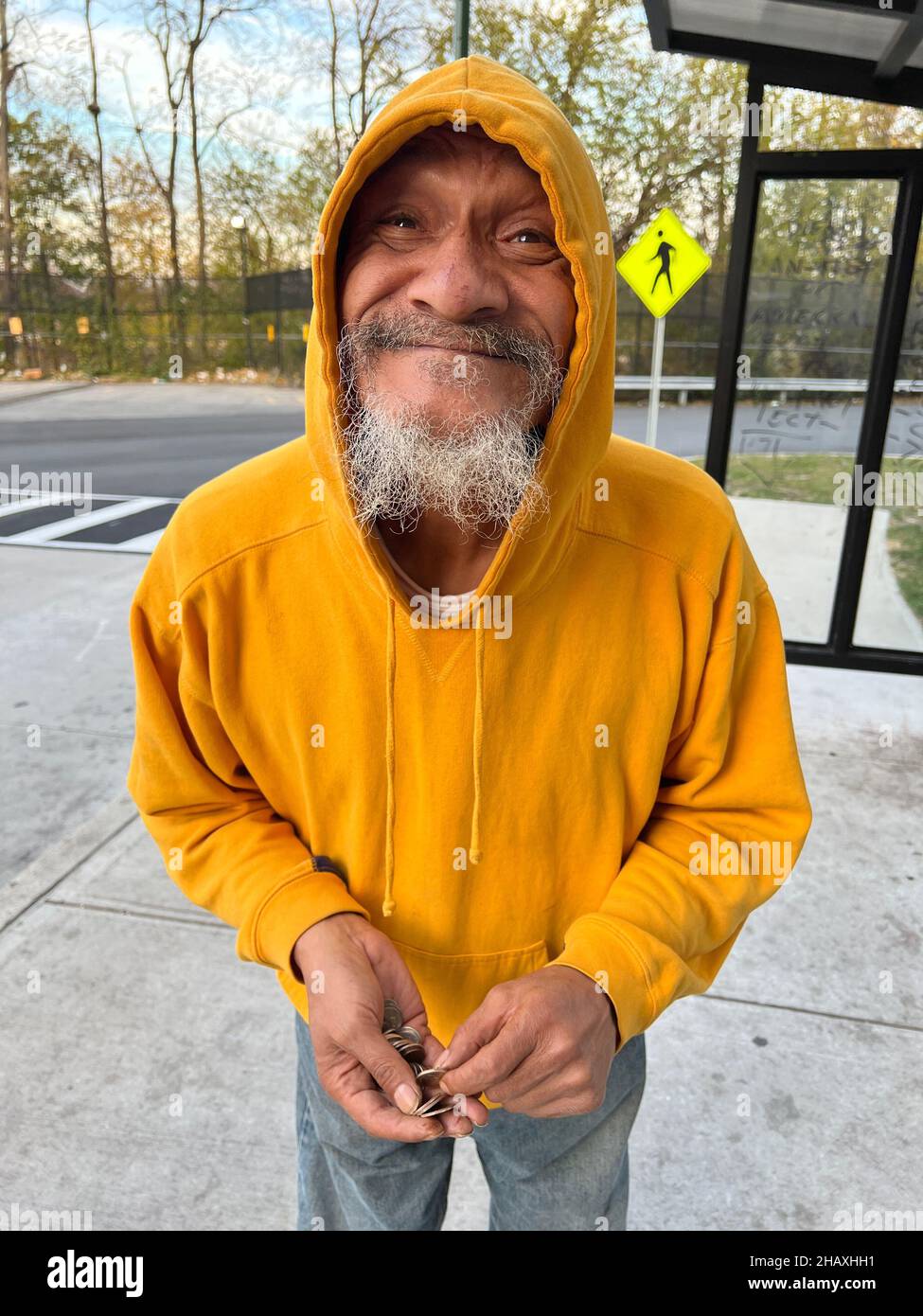 Portrait of a friendly panhandler with change in hand at a bus stop on ...