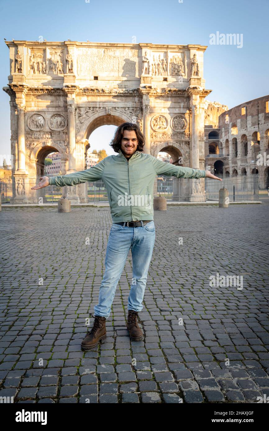 Happy moment in Rome. Young smiling man posing for a photo spreading ...