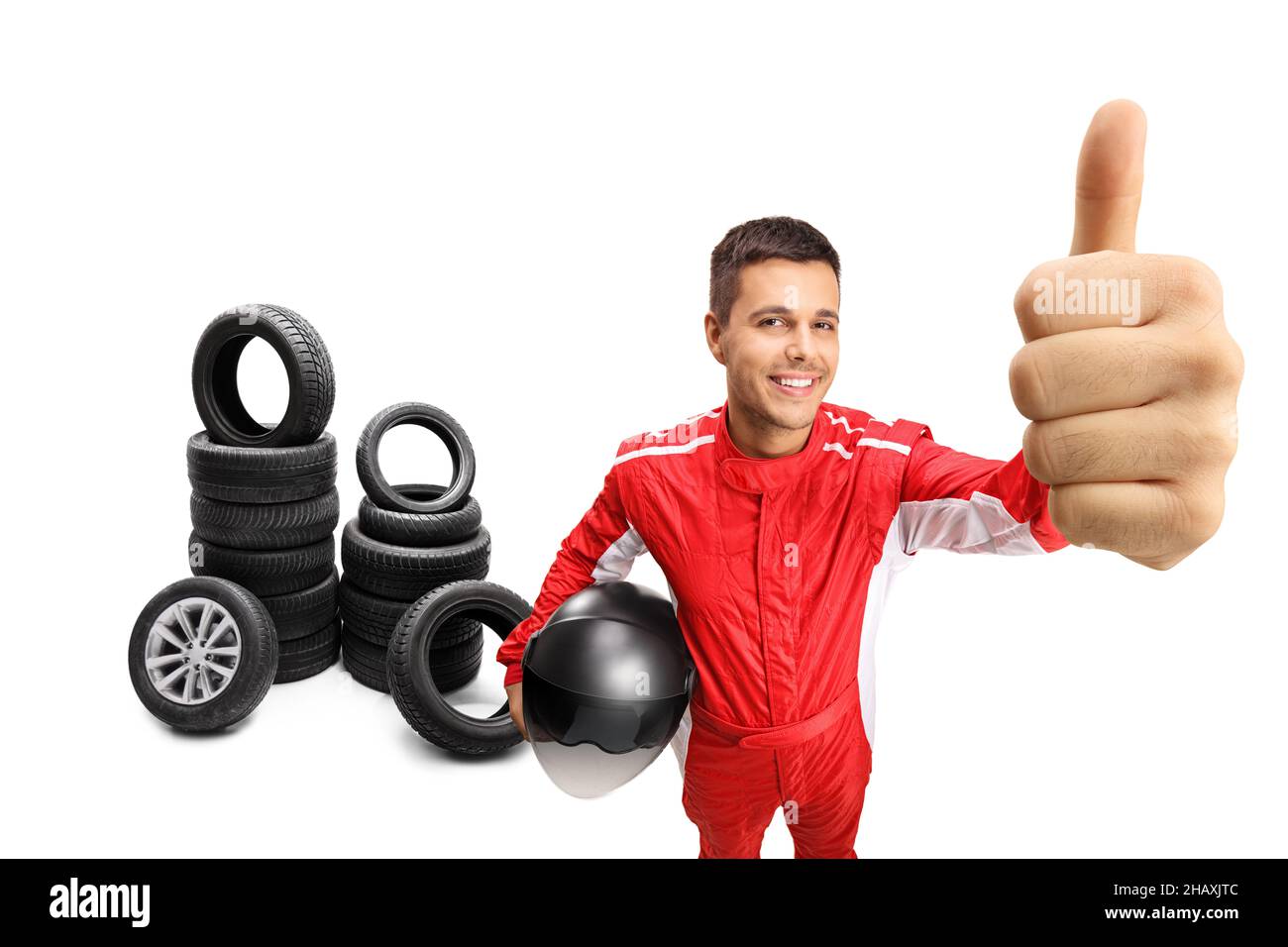 Racer holding a helmet and showing thumbs up with vehicle tires behind ...