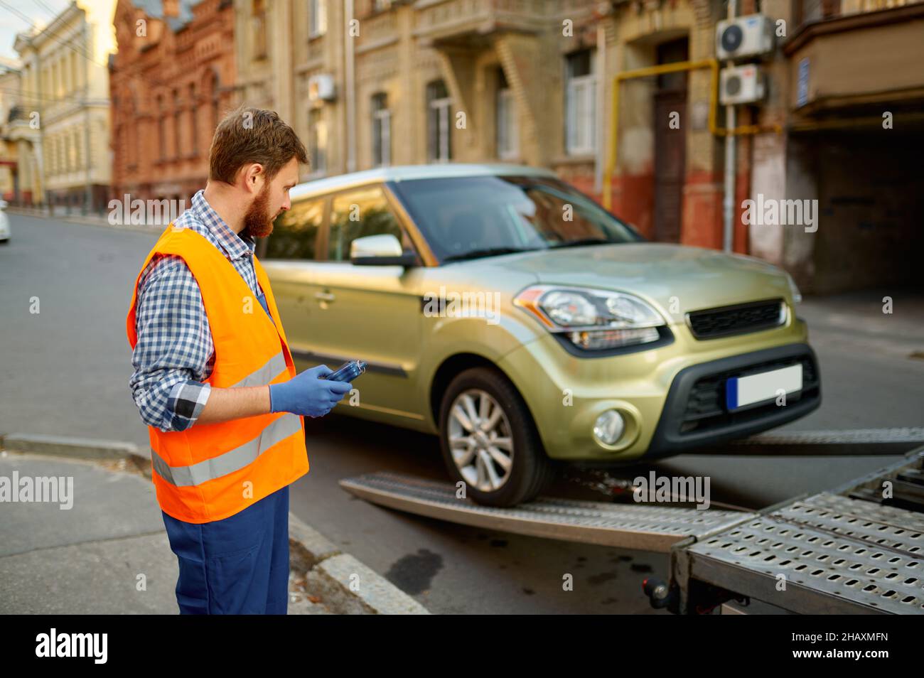 Male road worker monitoring car loading process Stock Photo - Alamy