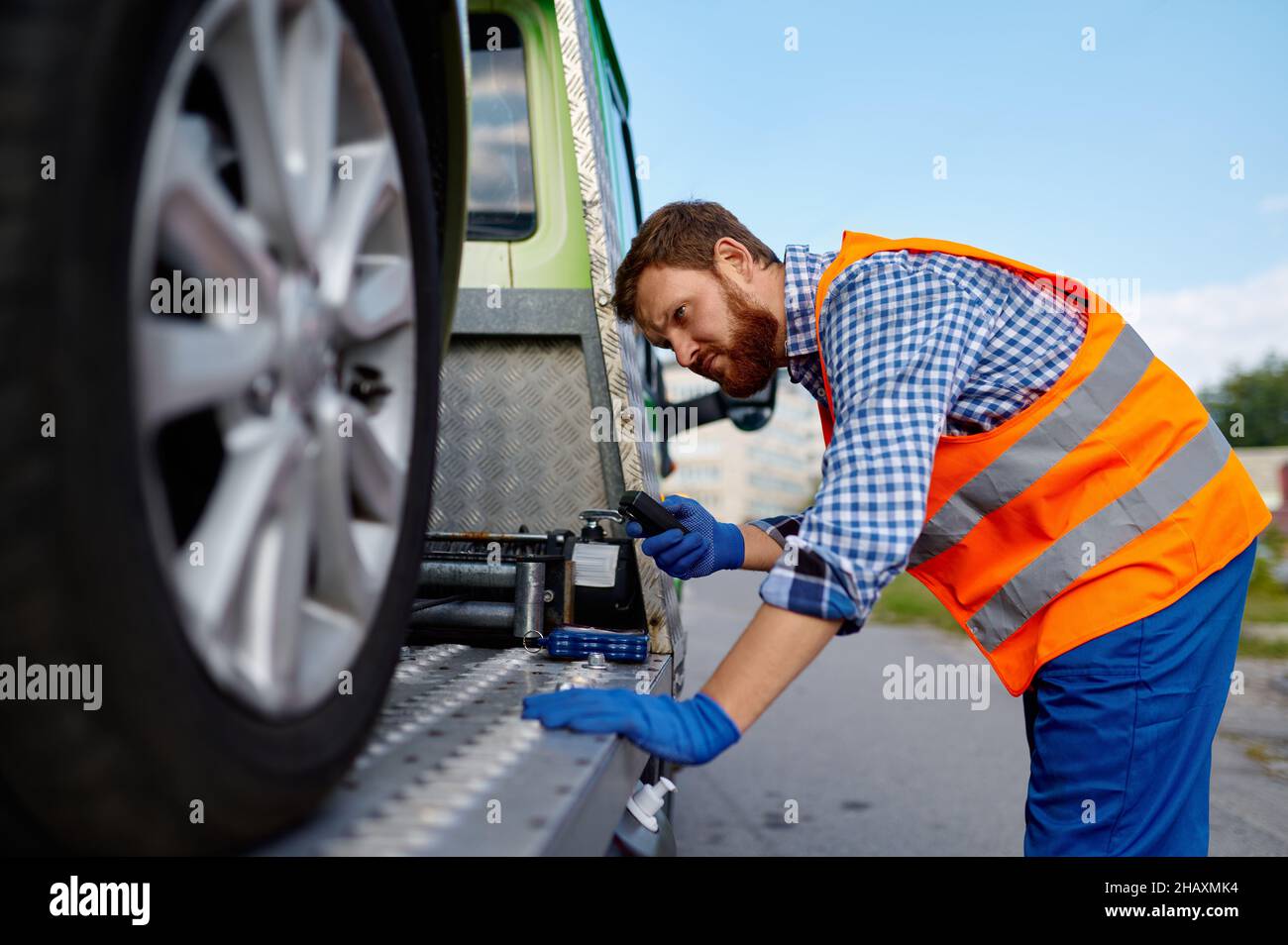 Tow truck operator fixing the car on platform Stock Photo - Alamy