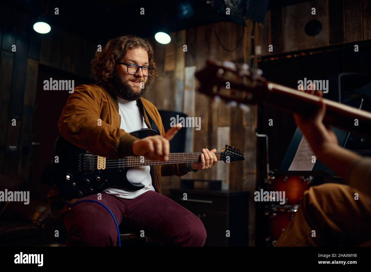 Musician teaching guy playing guitar at studio Stock Photo - Alamy