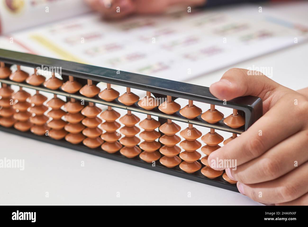 Doing mental math or mental arithmetic. Hand of little boy using abacus for calculating ...