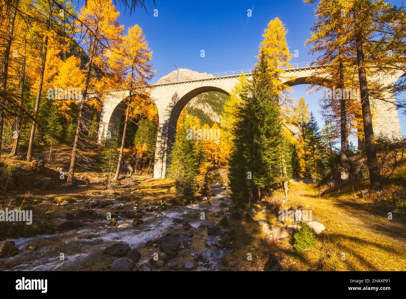 Railway bridge over an alpine stream and autumn landscape, Graubunden ...