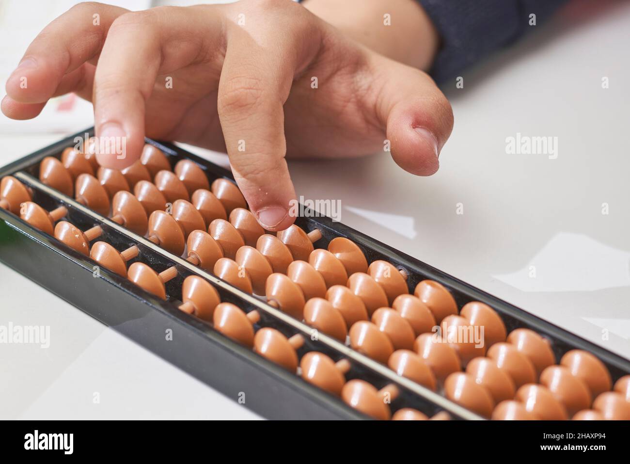 Doing mental math or mental arithmetic. Hand of little boy using abacus for calculating ...