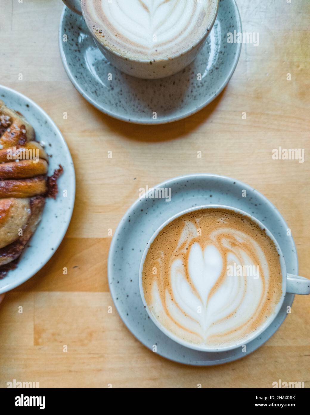 Top view of two cups of fresh cappuccino with heart foamand a sweet ...