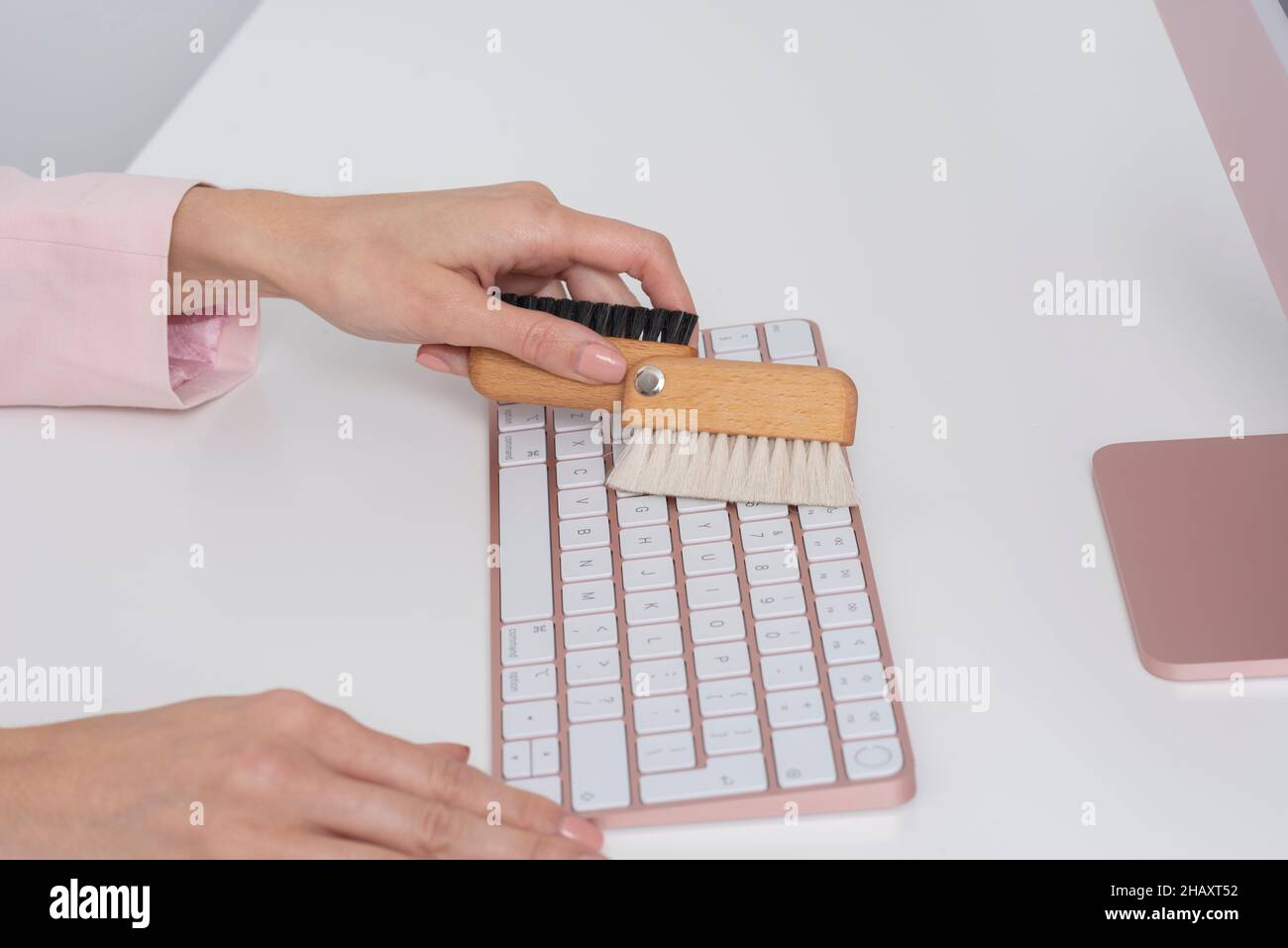 England, UK. 2021. Woman's hand holding and brushing clean a computer ...