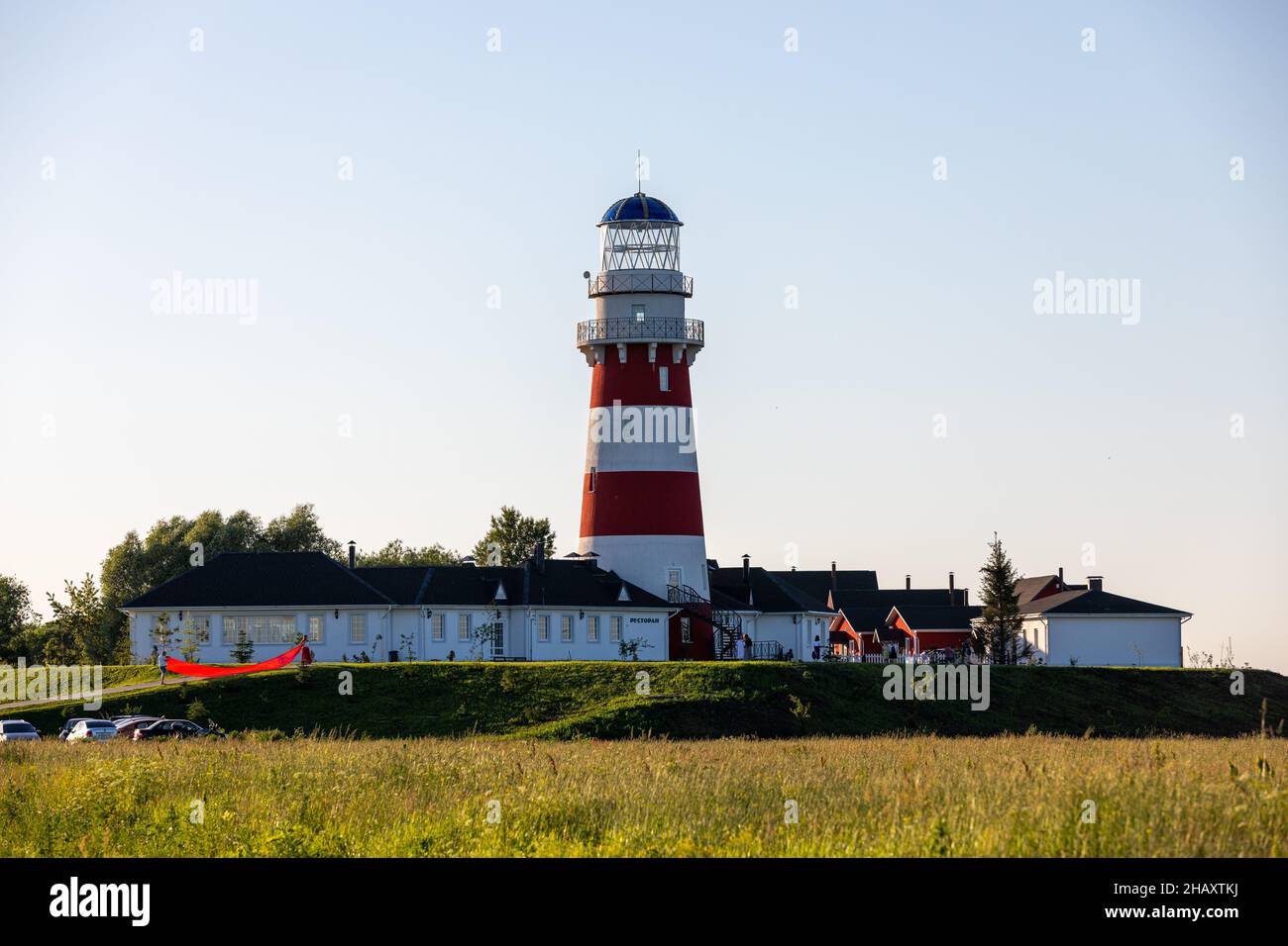 Lighthouse in red and white colors on the seashore, river bank or lake ...