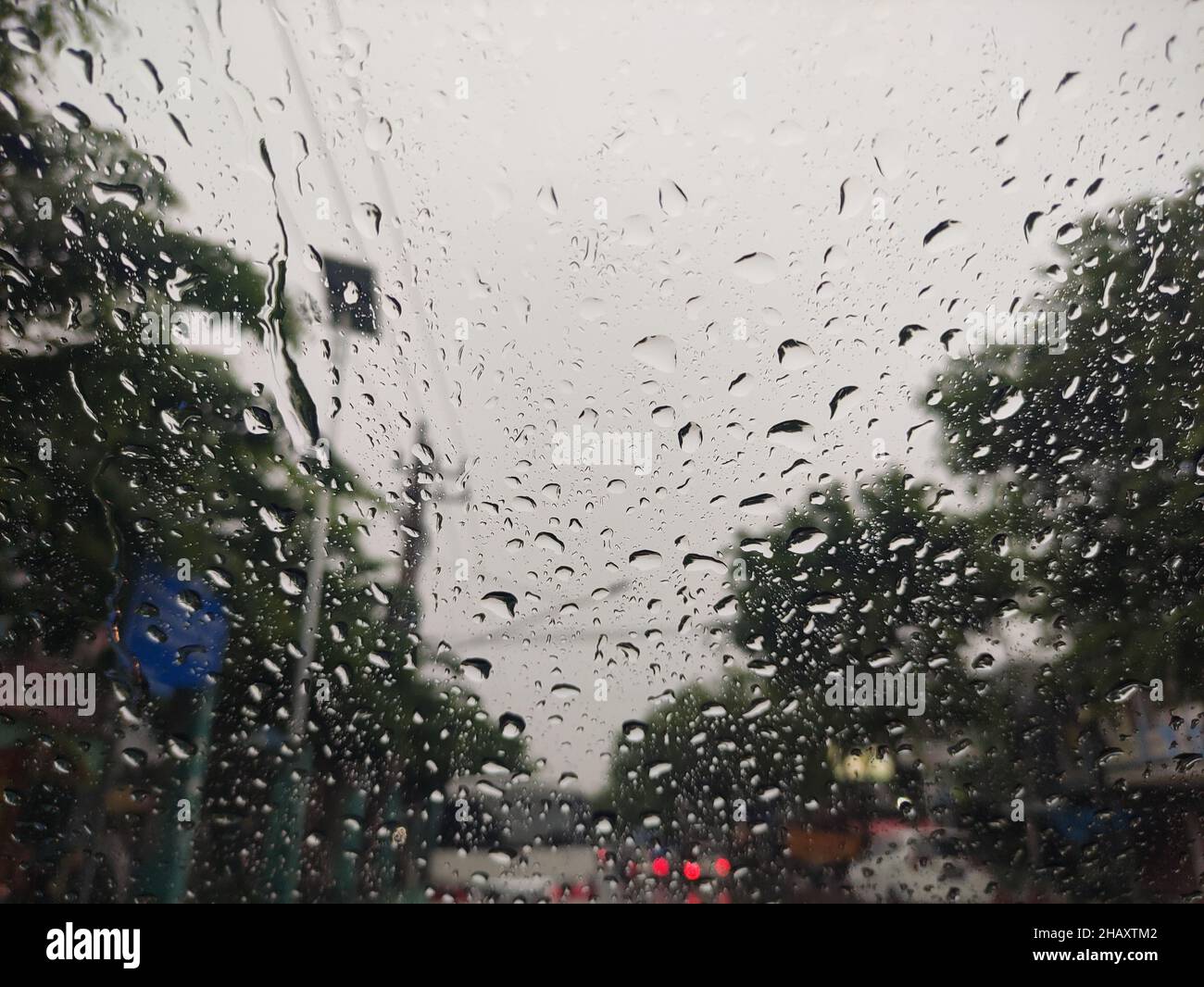 raindrops on the car window with a cloudy sky in the afternoon. taking ...