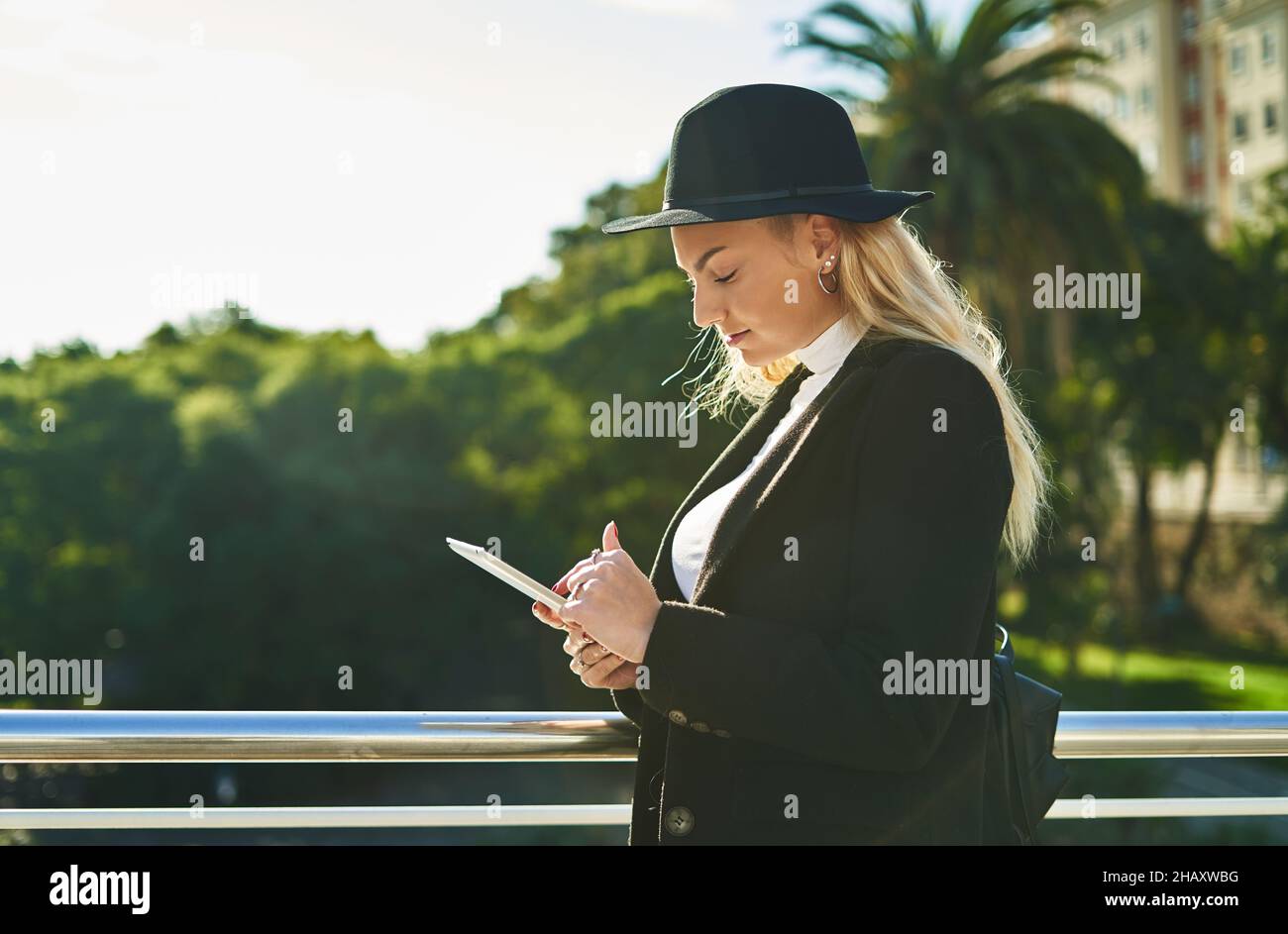Female barkeeper in stylish outfit adding ice cubes into a glass while ...