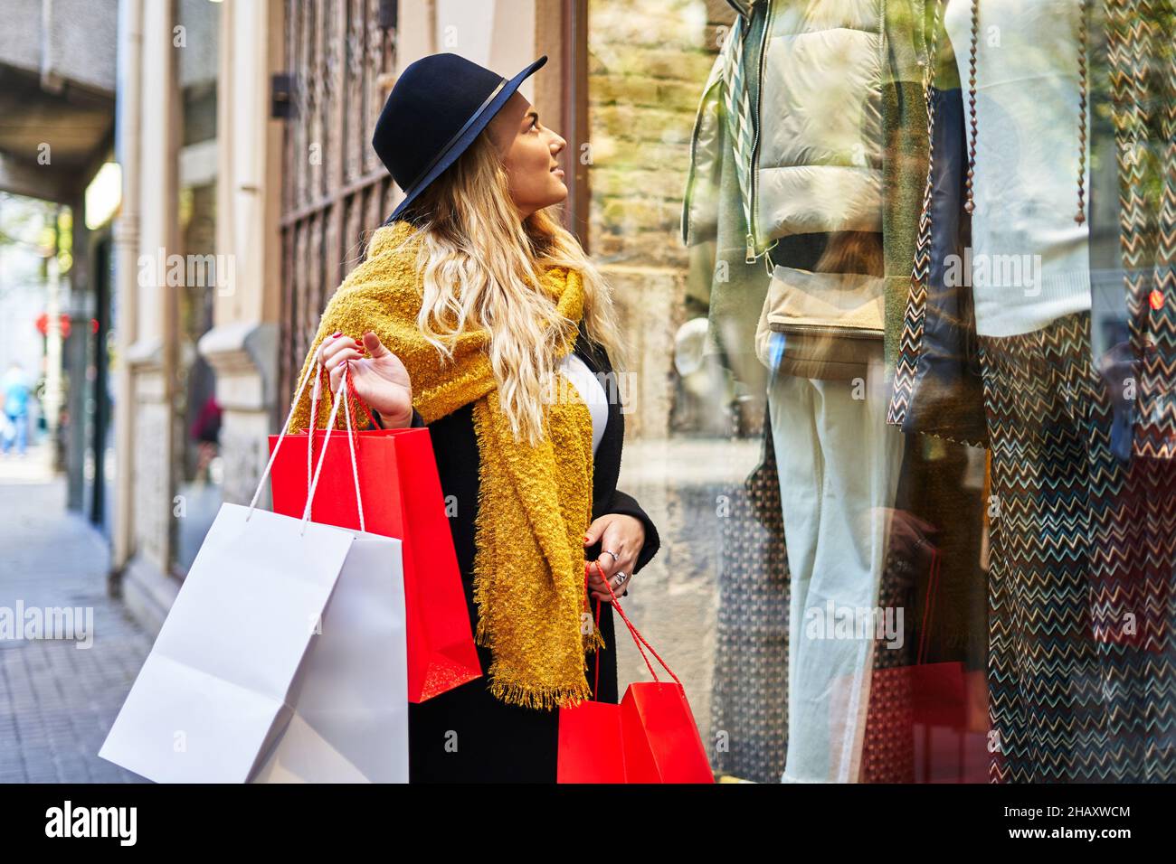 Positive young stylish female with colorful paper shopping packets ...