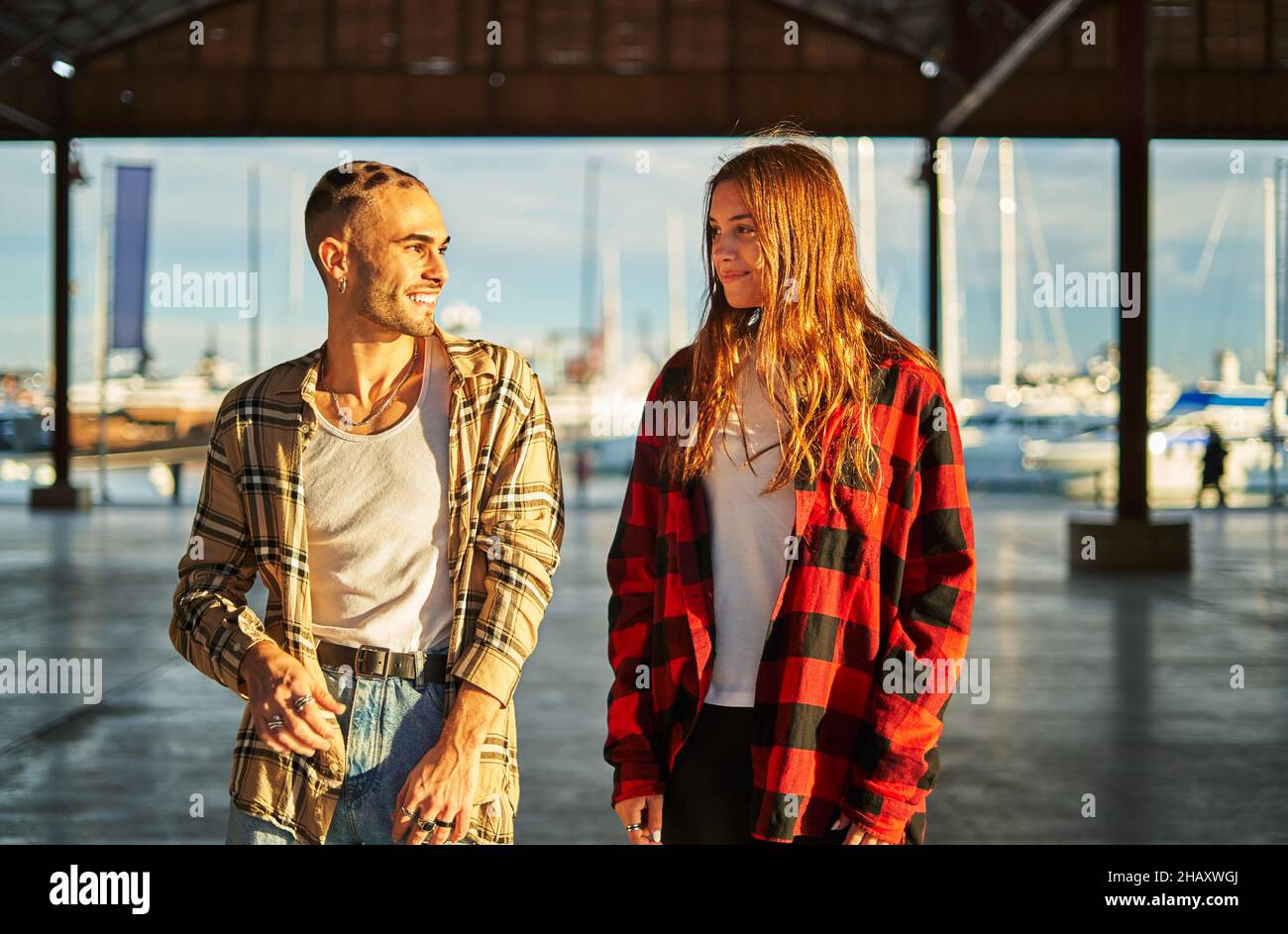 Positive eccentric man smiling widely while looking at female friend ...