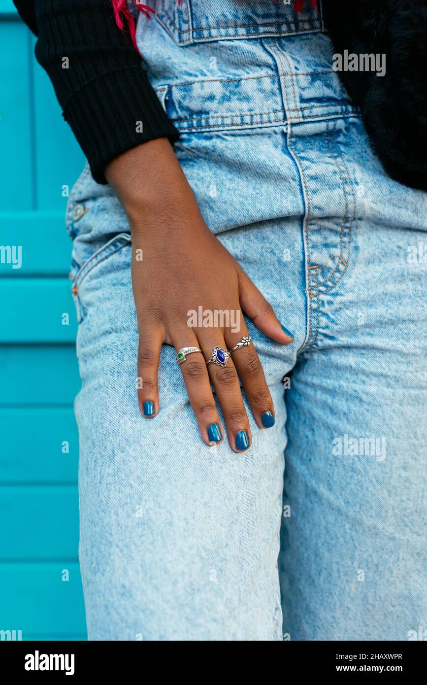 Unrecognizable crop African American Woman in denim putting hand on leg ...