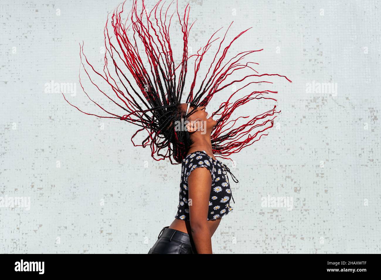 Side view of stylish African American Woman smiling while flipping long ...