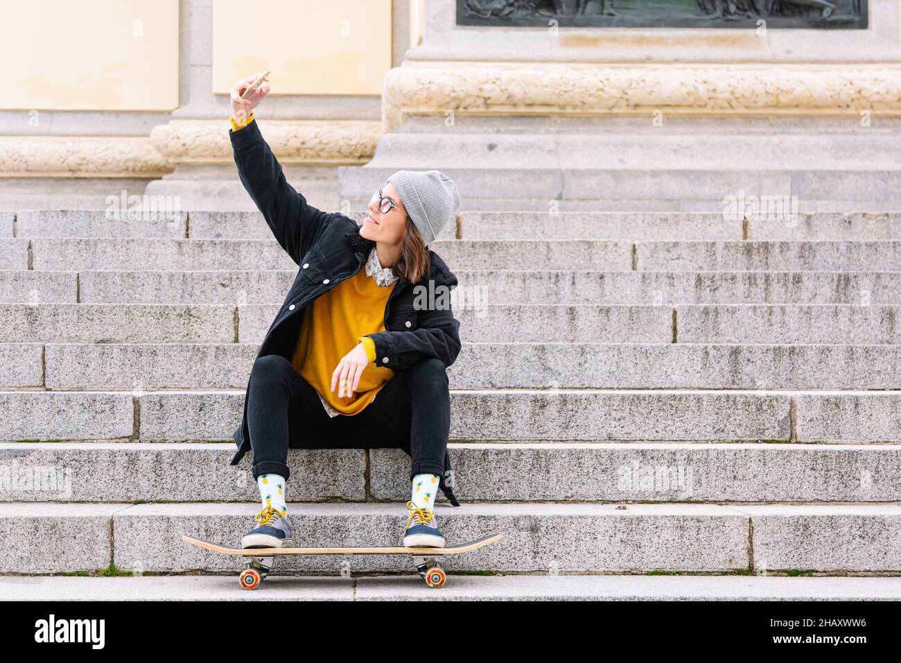 Full body of young positive female skater with legs on skateboard ...