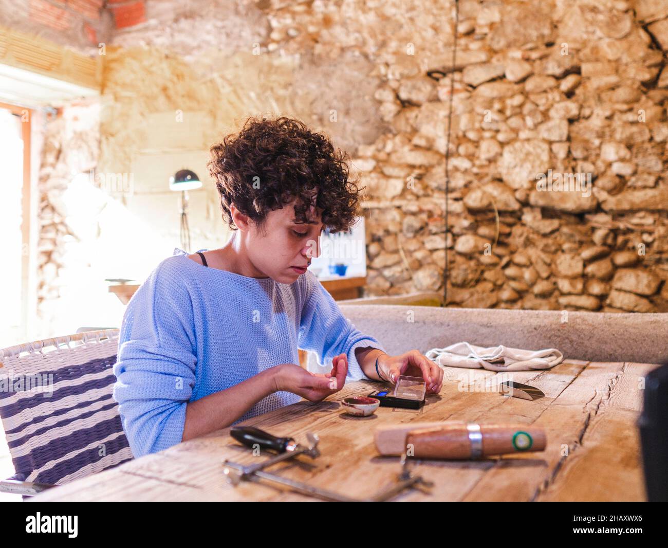 Side view of Hispanic curly female goldsmith holding gemstones in hand ...