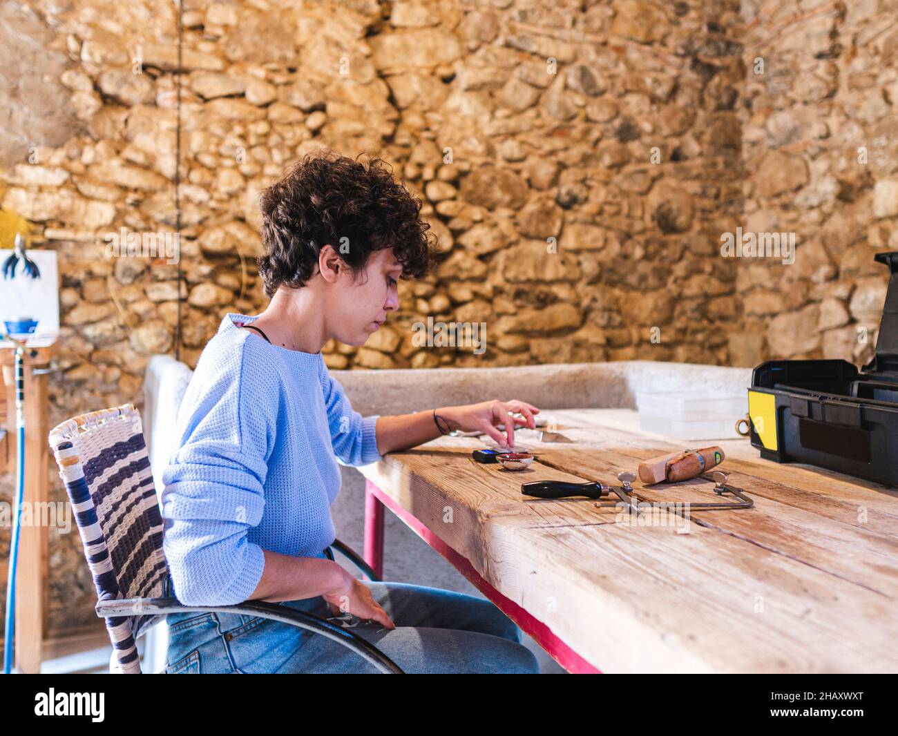 Side view of Hispanic curly female goldsmith holding gemstones in hand ...