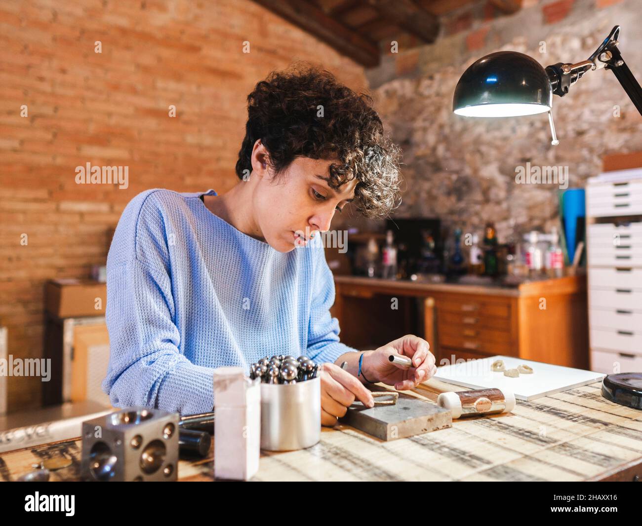 Hispanic concentrated female goldsmith working with precious details ...