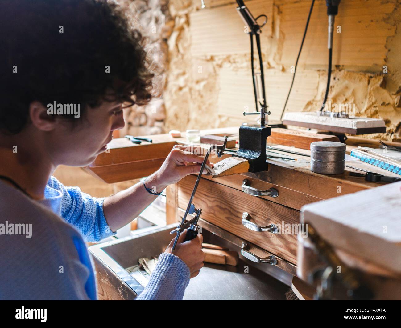Crop focused Hispanic female goldsmith master using manual fretsaw ...