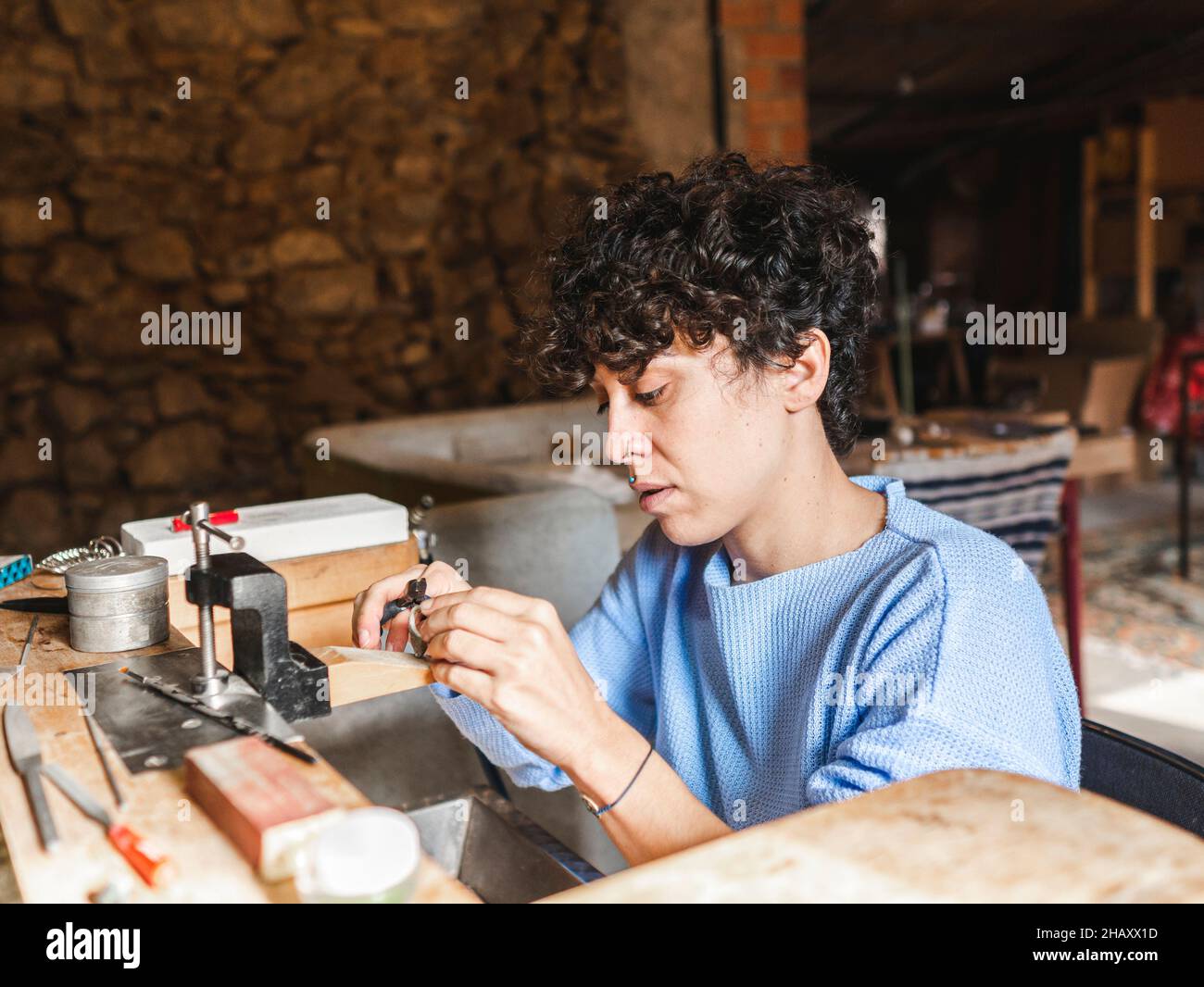 Female master making ring with pliers while putting jewelry on wooden ...