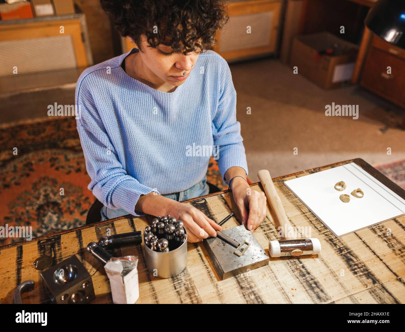 High angle of female ethnic artisan sitting at table and preparing ...