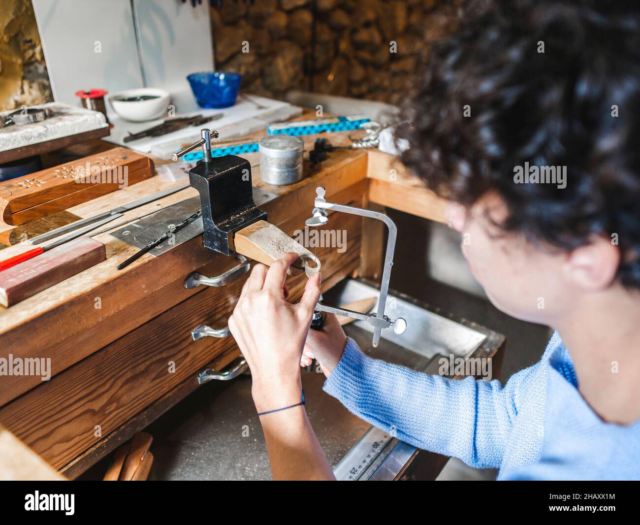 Crop focused Hispanic female goldsmith master using manual fretsaw ...